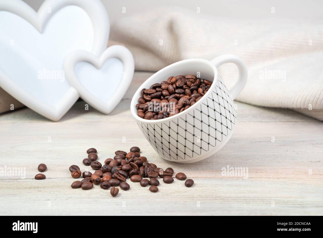 Coffee beans spill out of a tilted Cup on a light background. Side view ...