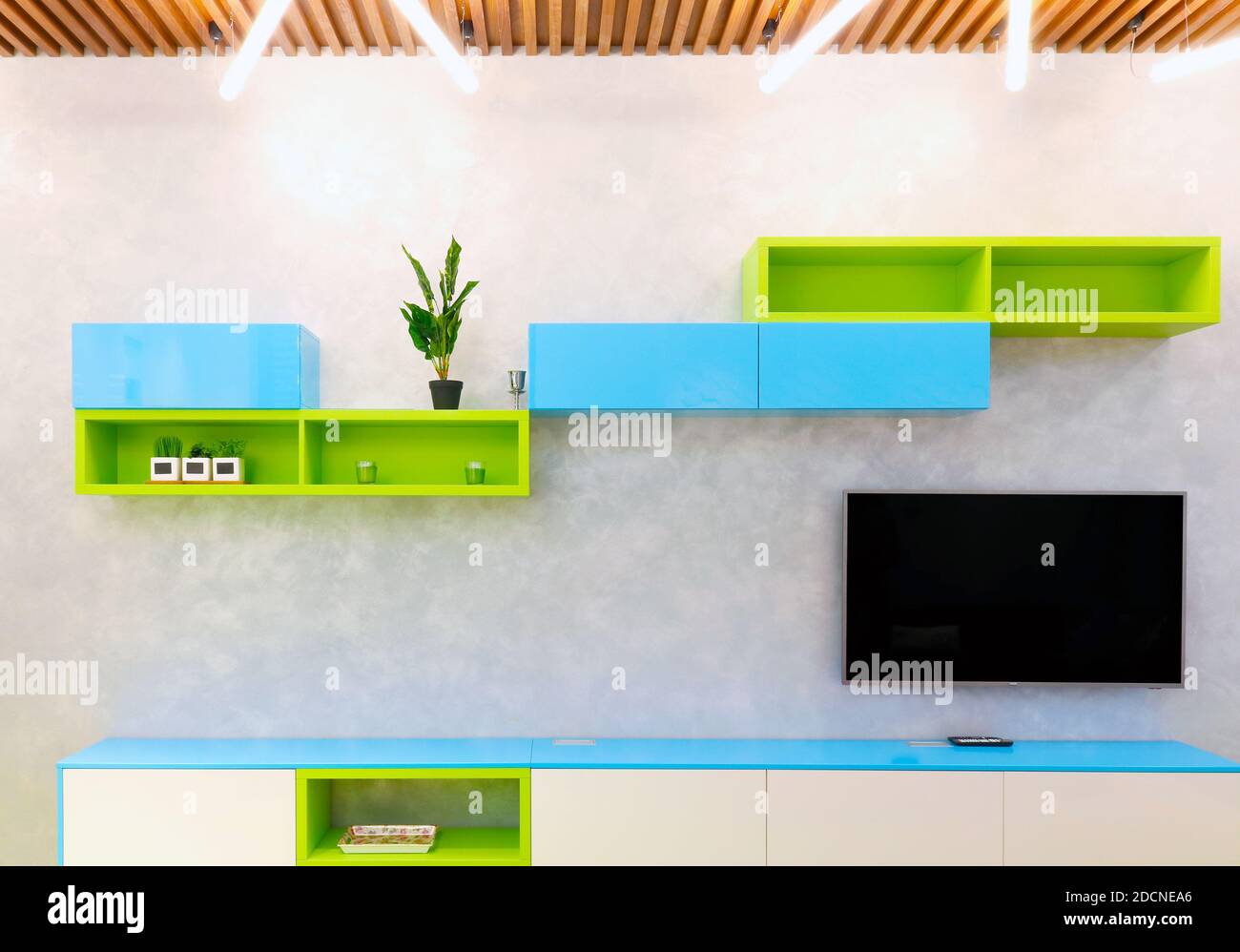 Blue and green shelves with screen hanging on contemporary wall. Wooden ...