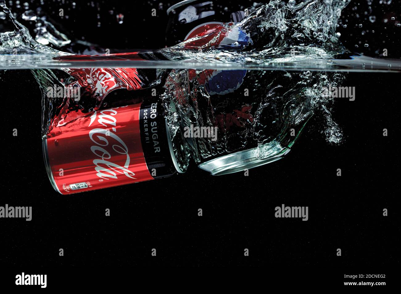 Close up view of coca and pepsi falling in water on black background ...