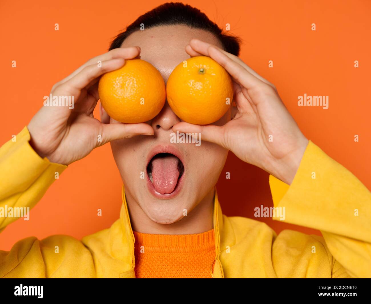 Surprised guy with oranges in front of his eyes opened his mouth wide ...