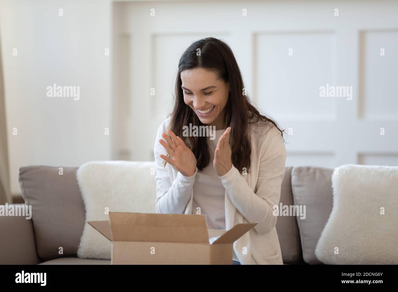 Excited young woman shopper unboxing parcel shipped by mail Stock Photo ...
