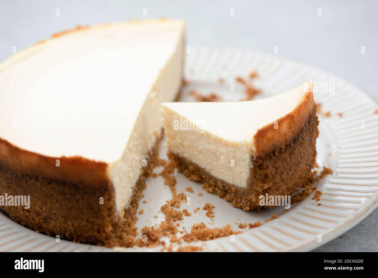Plain new york cheesecake with slice cut out on a plate, closeup view ...