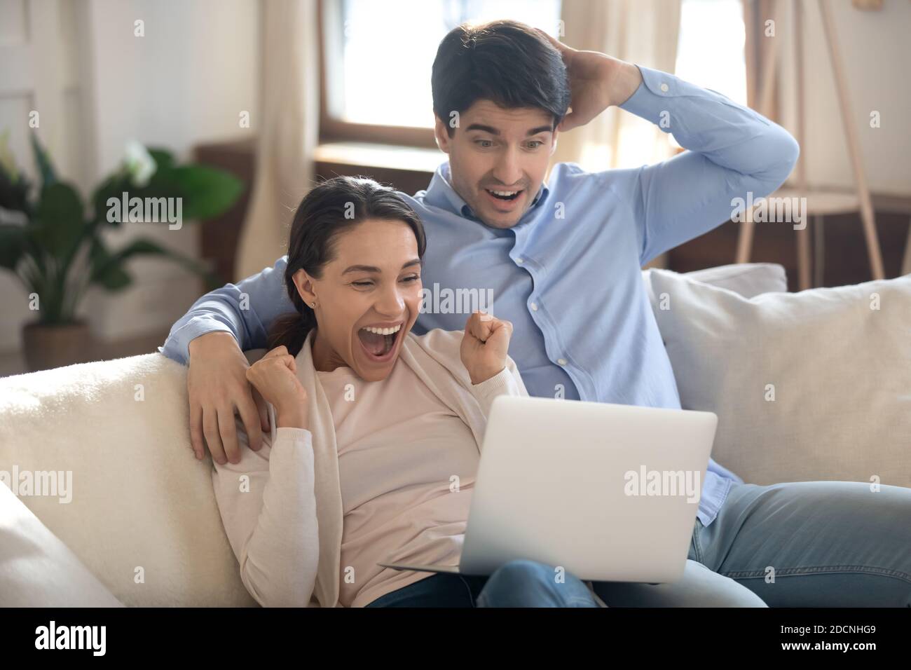 Excited young spouses football fans watching soccer match using laptop ...