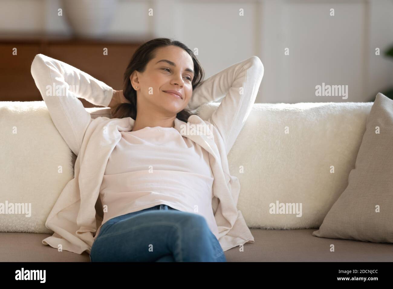 Successful woman resting on sofa looking aside with dreamy smile Stock ...
