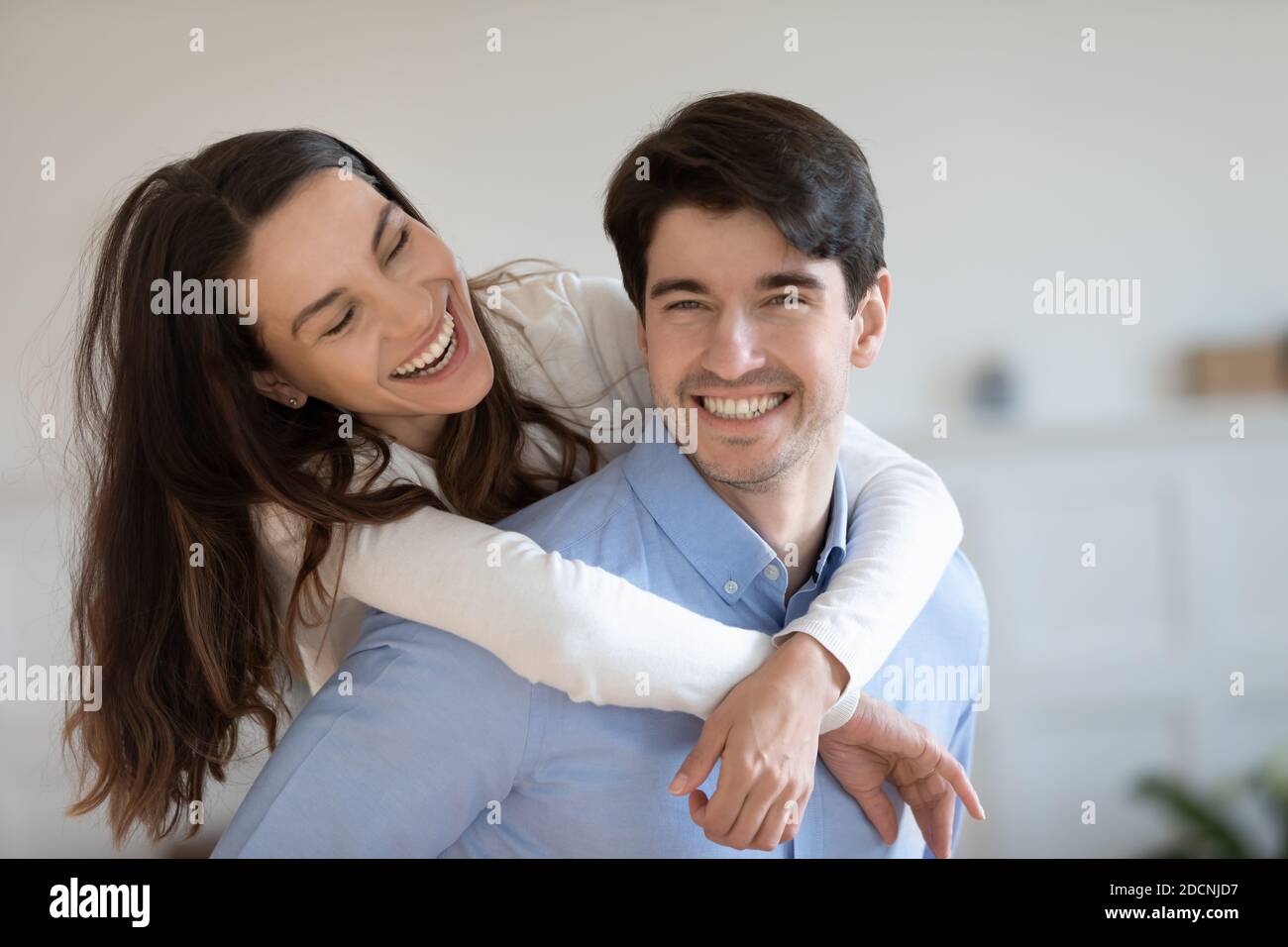 Funny portrait of millennial boyfriend holding joyful girlfriend on ...