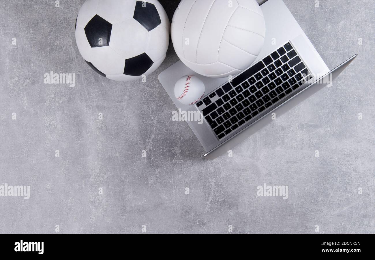 Soccer, volleyball and baseball ball and grey laptop on grey background ...