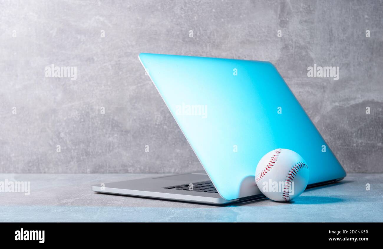 Baseball ball and grey laptop on grey background. Online workout ...