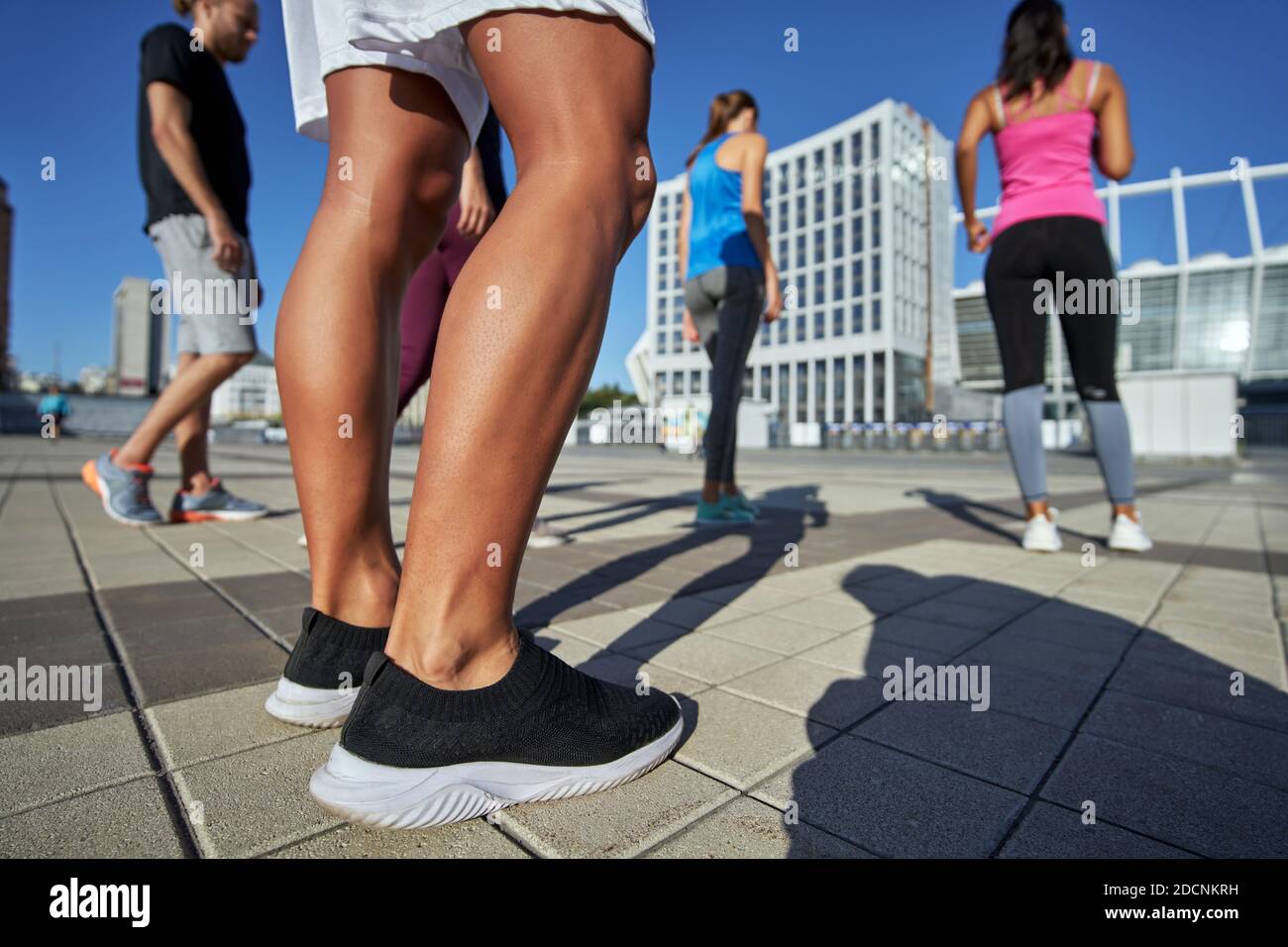 Strong legs of male runner on team members background Stock Photo - Alamy