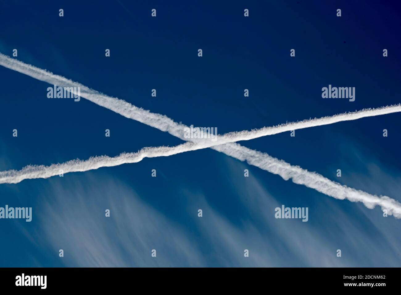 Jet contrails crossing each other in a blue sky Stock Photo - Alamy