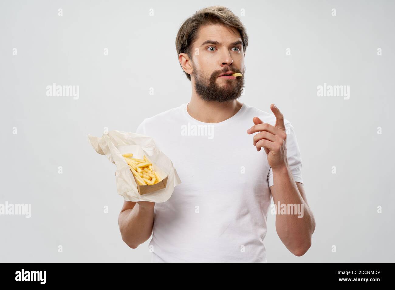 Bearded man holding fast food fries in his hands food Stock Photo - Alamy