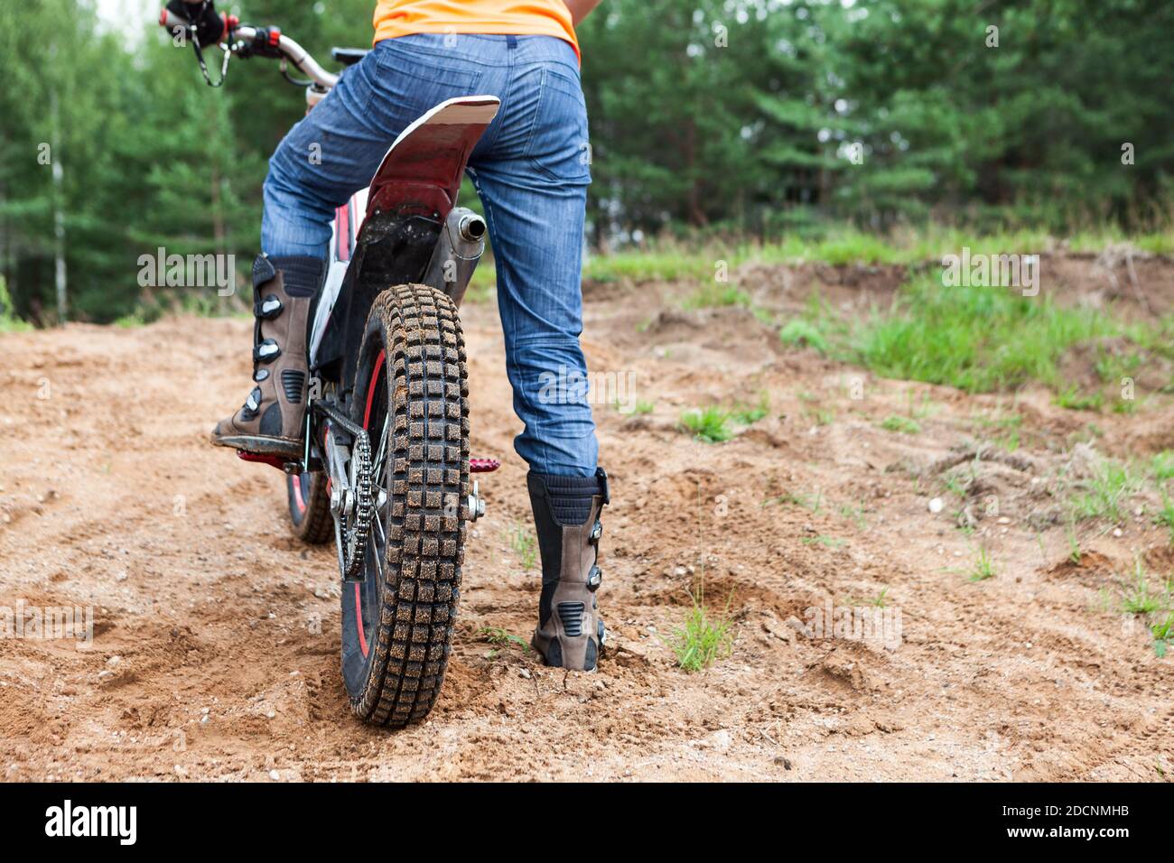 Mototrial rider standing on motorcycle in sand. Extreme sports on ...