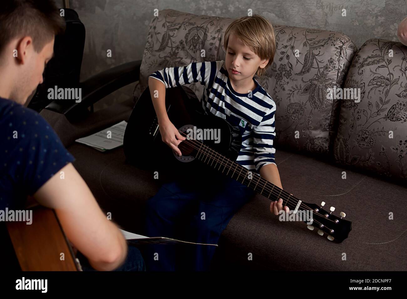 Young male musician teaches little boy student how to play the acoustic ...