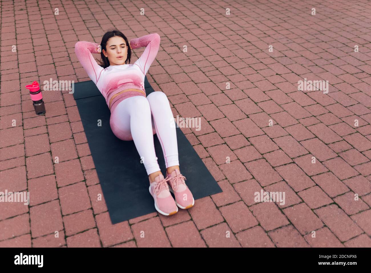 Beautiful Fitness Woman In Pink Sportswear Lying On Yoga Mat And Doing
