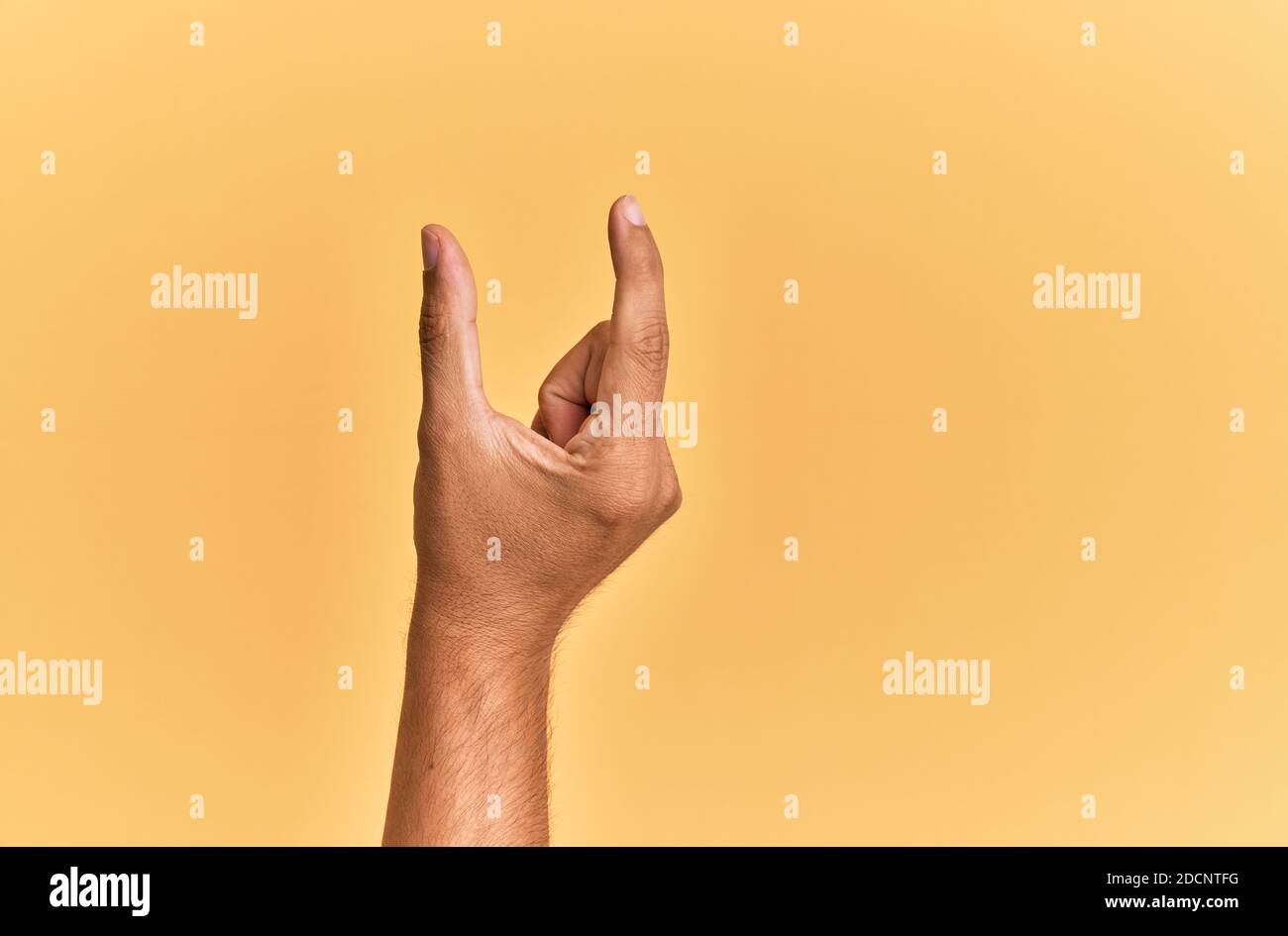 Arm and hand of caucasian man over yellow isolated background picking ...