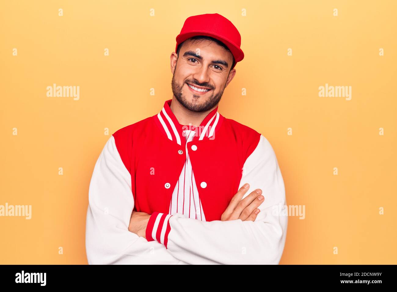 Handsome sporty man with beard wearing baseball jacket and cap over ...