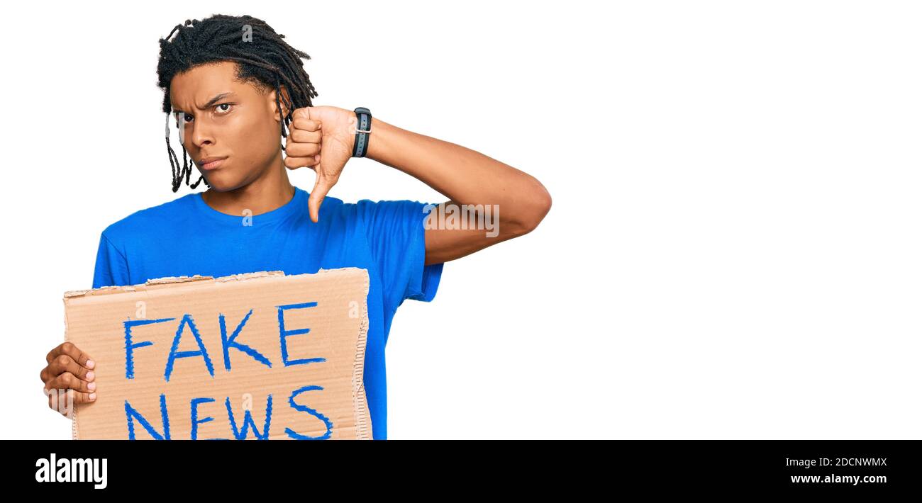 Young african american man holding fake news banner with angry face ...