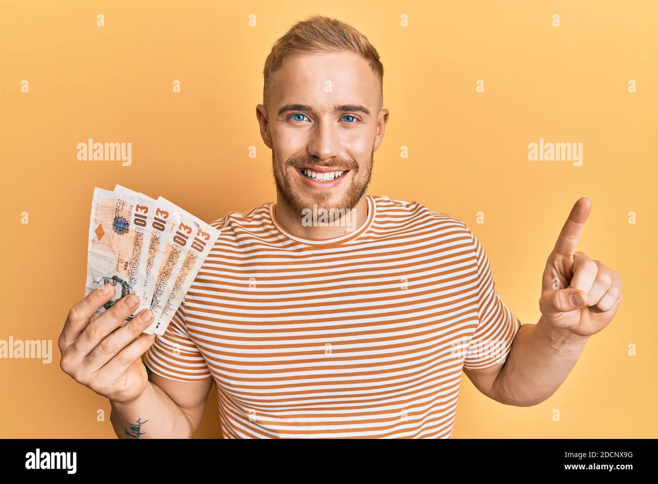 Young caucasian man holding 10 united kingdom pounds banknotes smiling ...