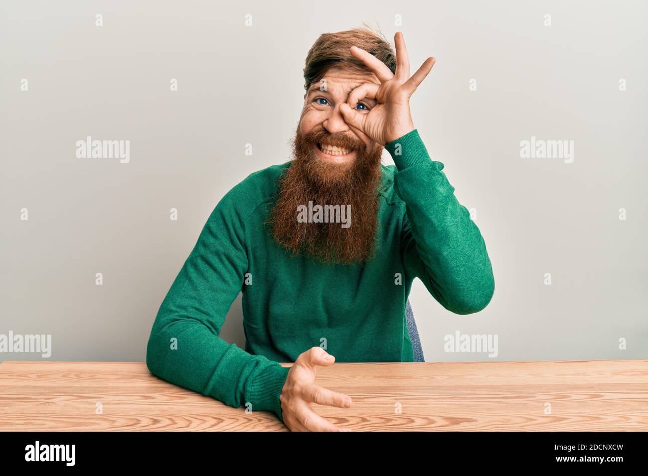 Young irish redhead man wearing casual clothes sitting on the table ...