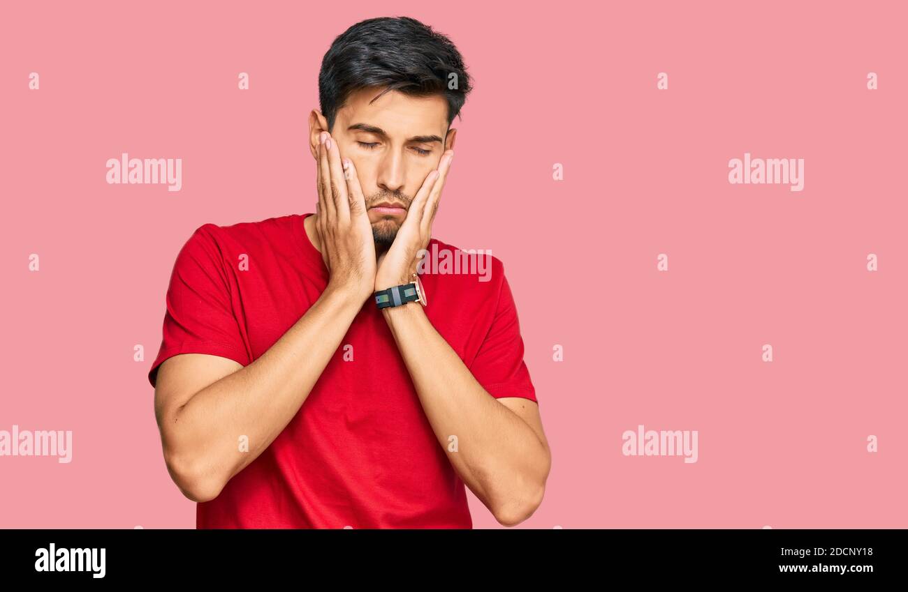 Young handsome man wearing casual red tshirt tired hands covering face ...