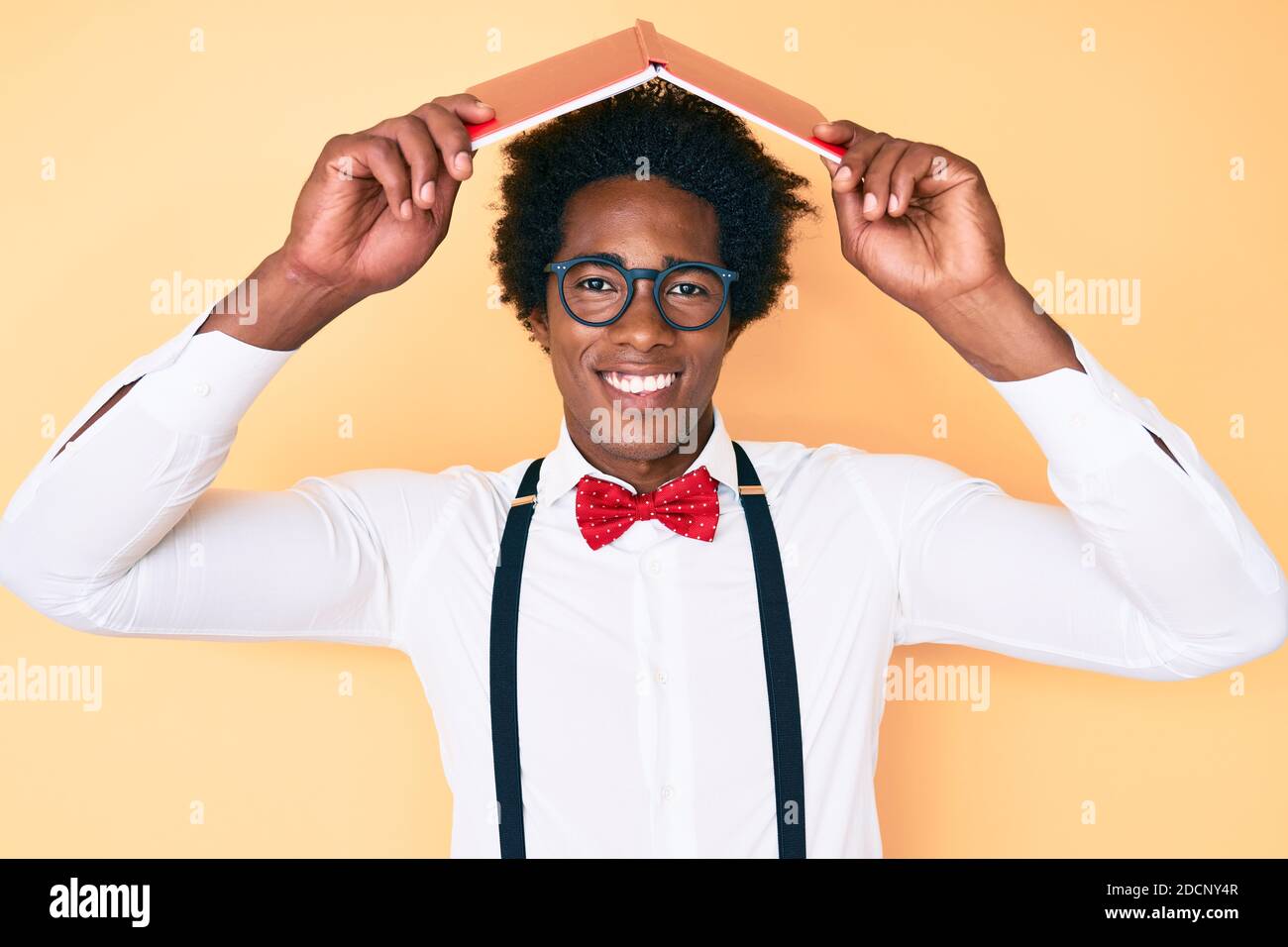 Handsome african american nerd man with afro hair holding book over ...