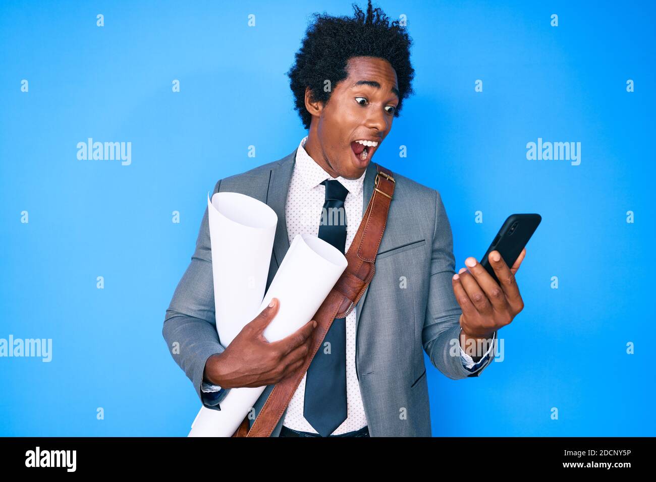Handsome african american man with afro hair holding paper blueprints ...