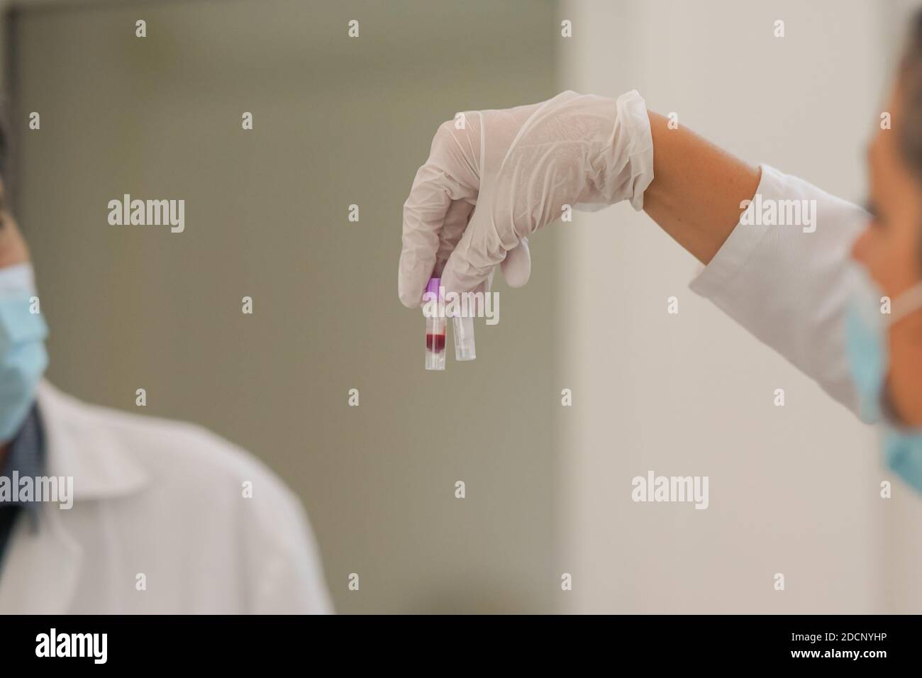 Female laboratory technician holding two test tubes with blood sample ...