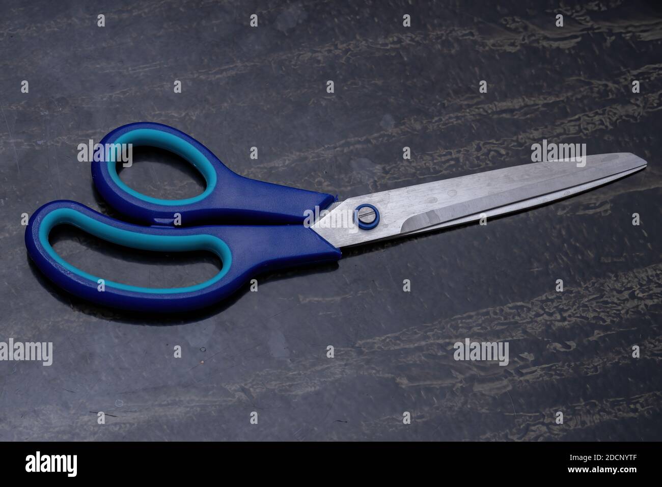 Blue long scissors with dark background Stock Photo - Alamy