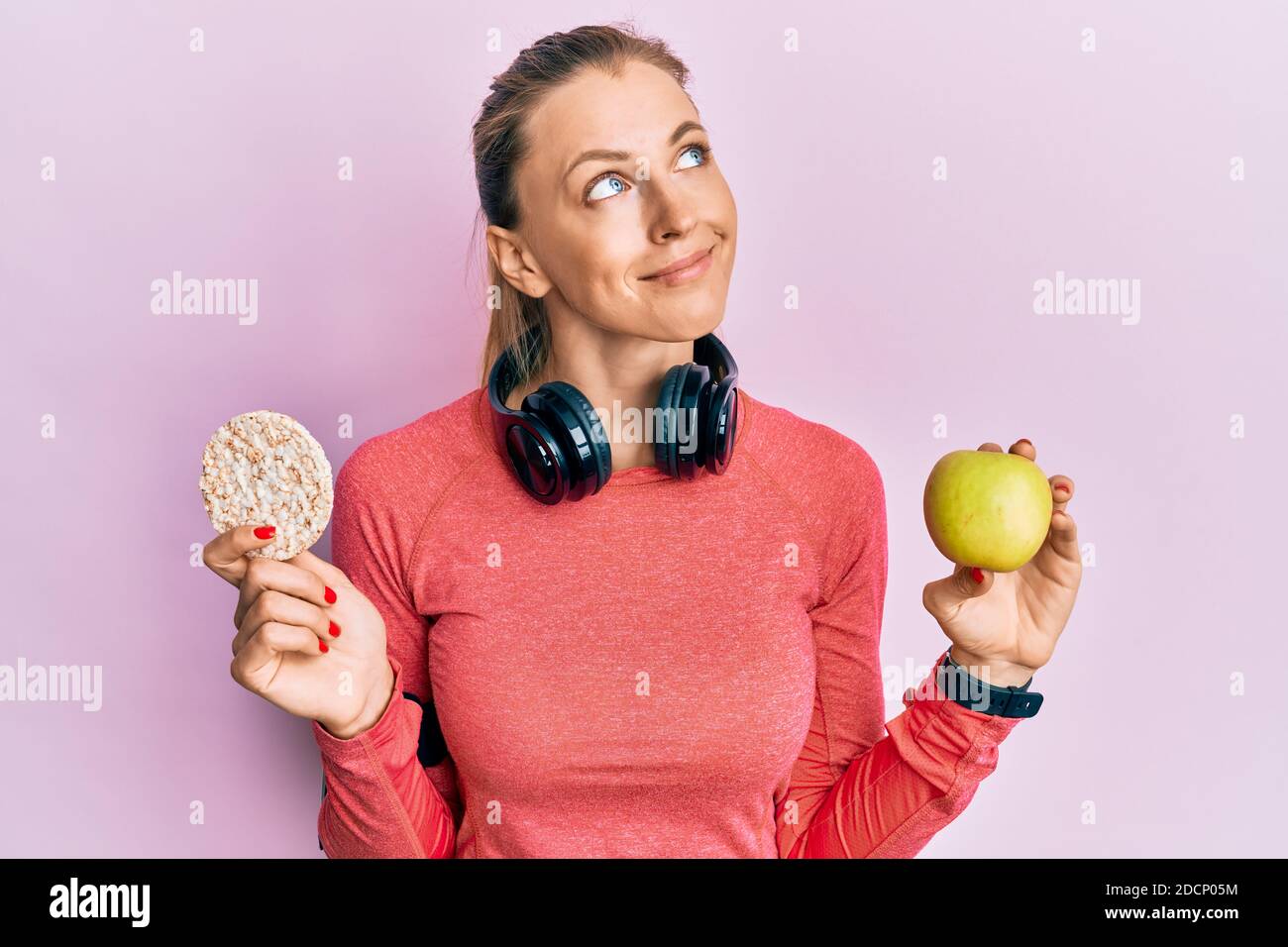 Beautiful caucasian sports woman holding green apple and rice crackers ...