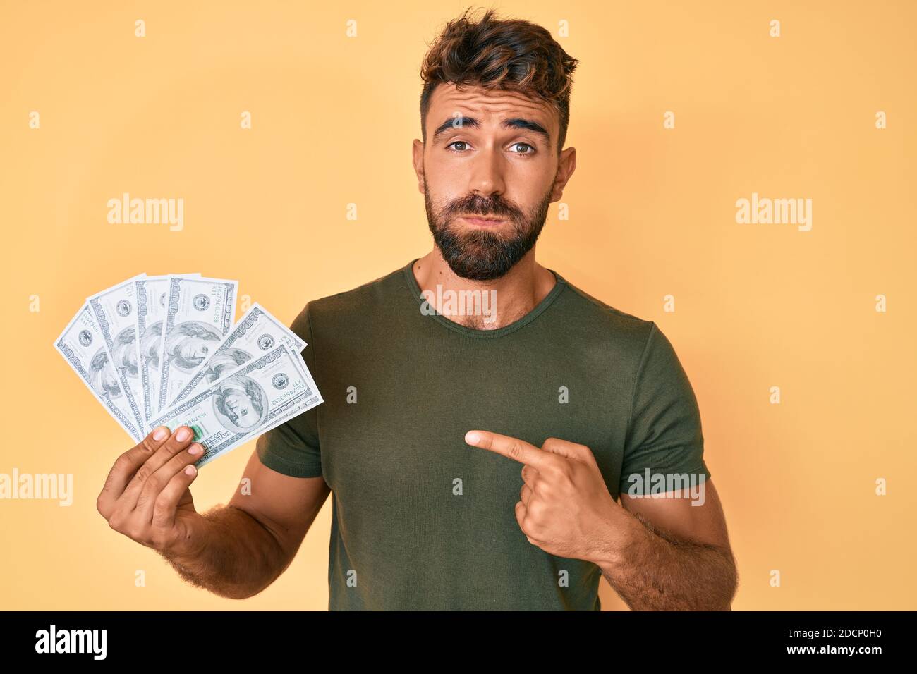 Young hispanic man holding dollars puffing cheeks with funny face ...