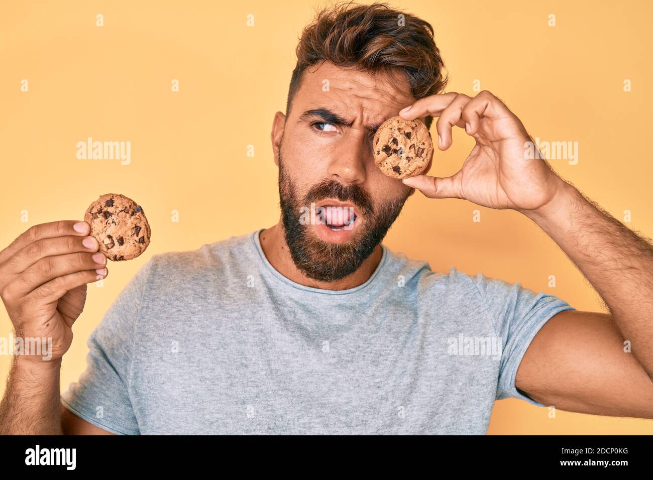 Young hispanic man holding cookie angry and mad screaming frustrated ...