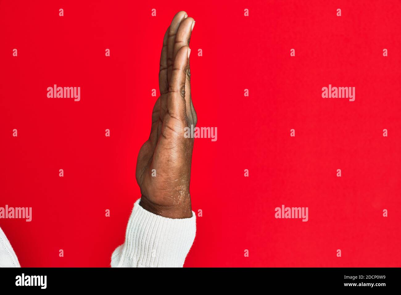 Arm and hand of african american black young man over red isolated ...