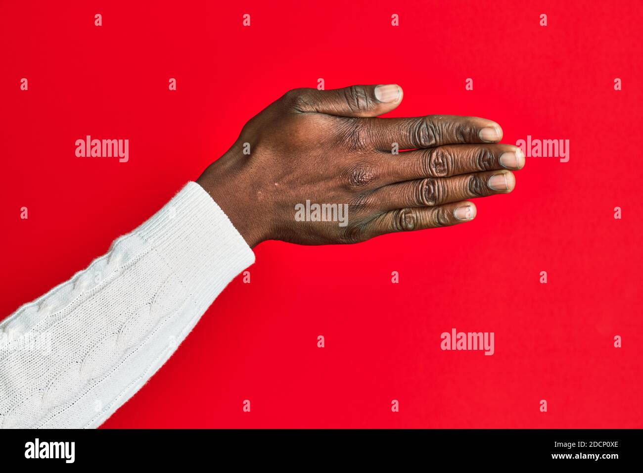 Arm and hand of african american black young man over red isolated ...