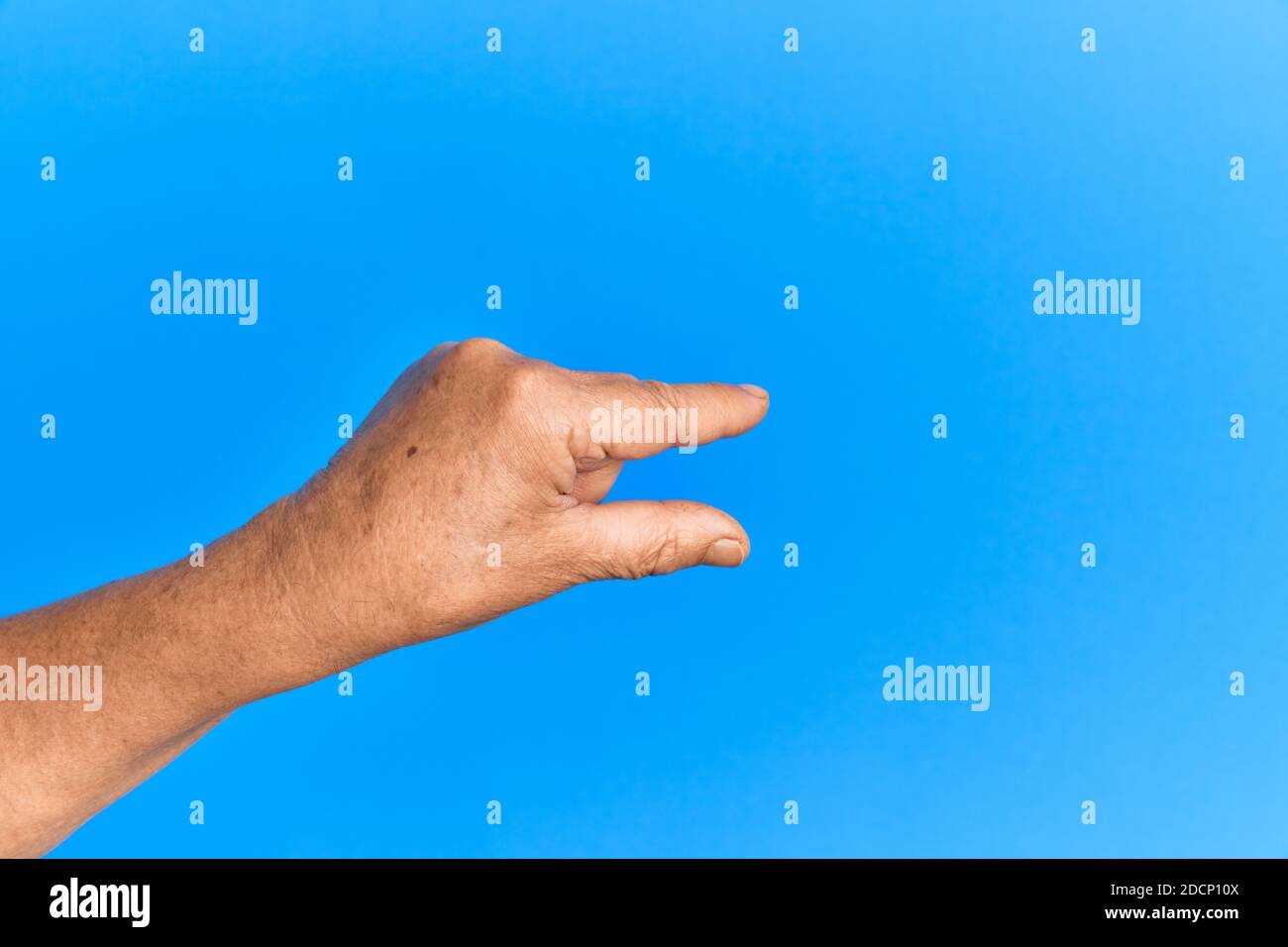 Senior man arm and hand over blue isolated background holding invisible ...
