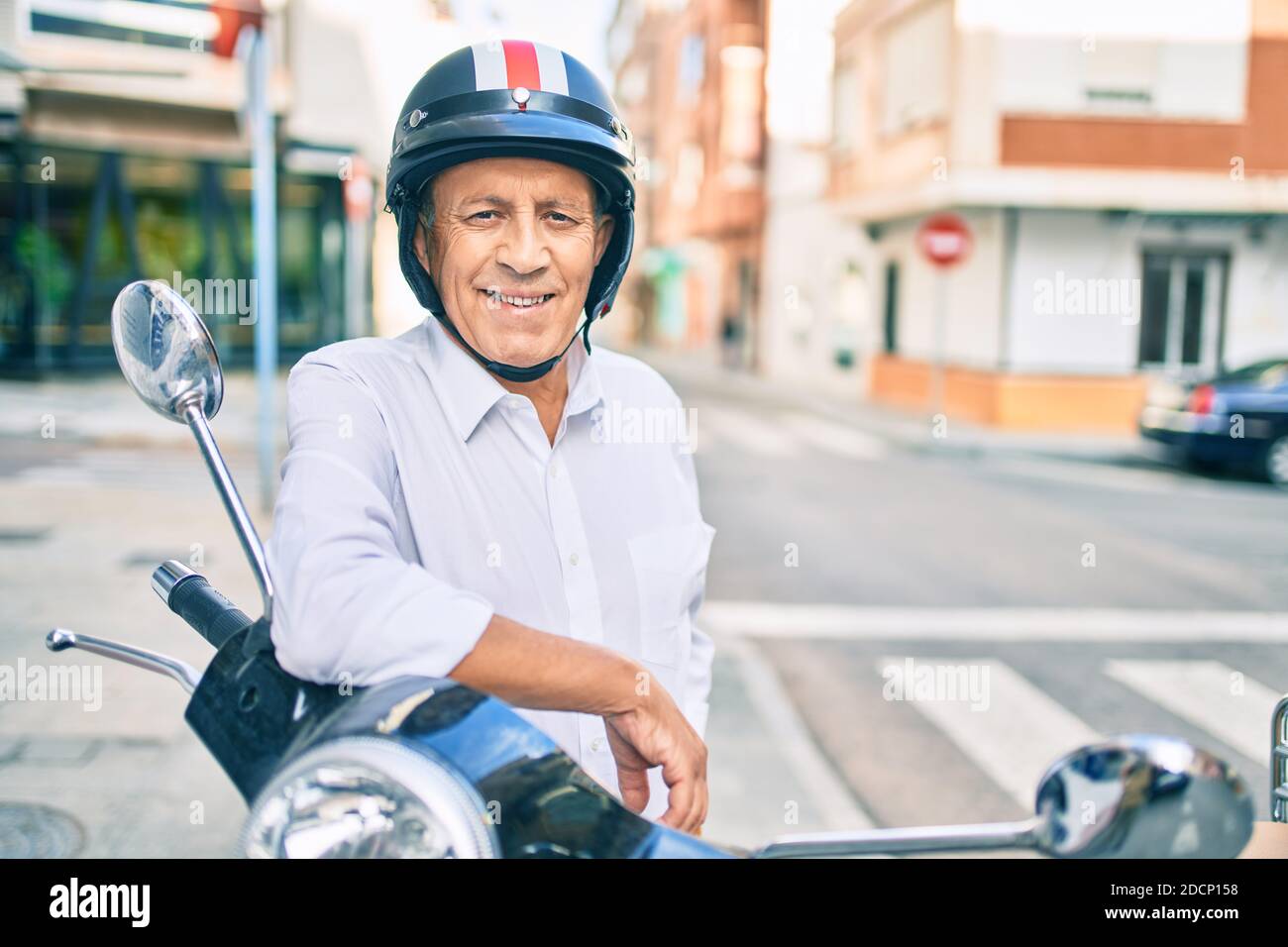 Senior motorcyclist man smiling happy wearing moto helmet at the city ...