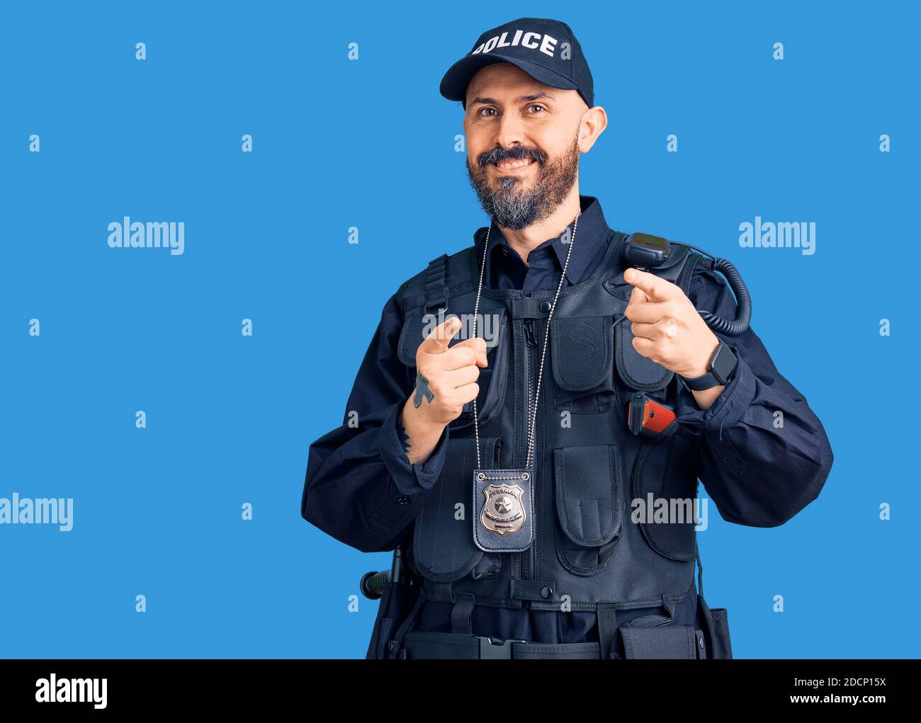 Young handsome man wearing police uniform pointing fingers to camera ...