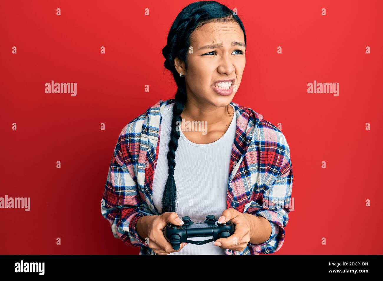Beautiful hispanic woman playing video game holding controller angry ...