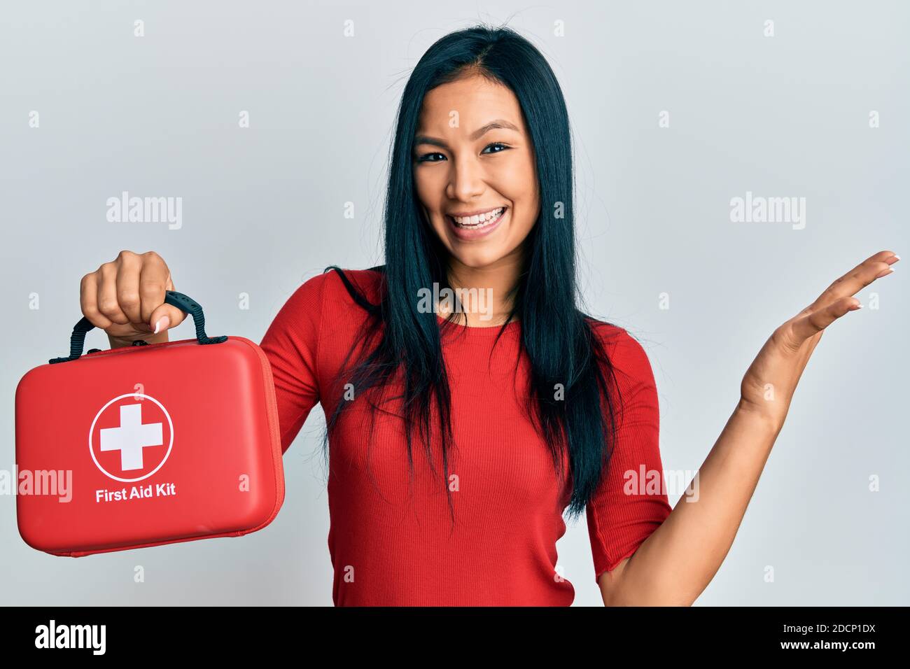 Beautiful hispanic woman holding first aid kit celebrating achievement ...