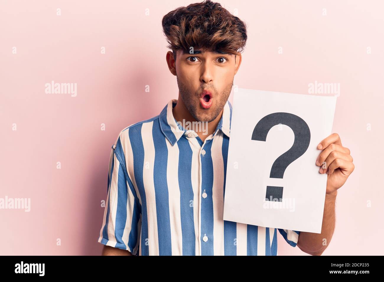 Young hispanic man holding question mark scared and amazed with open ...