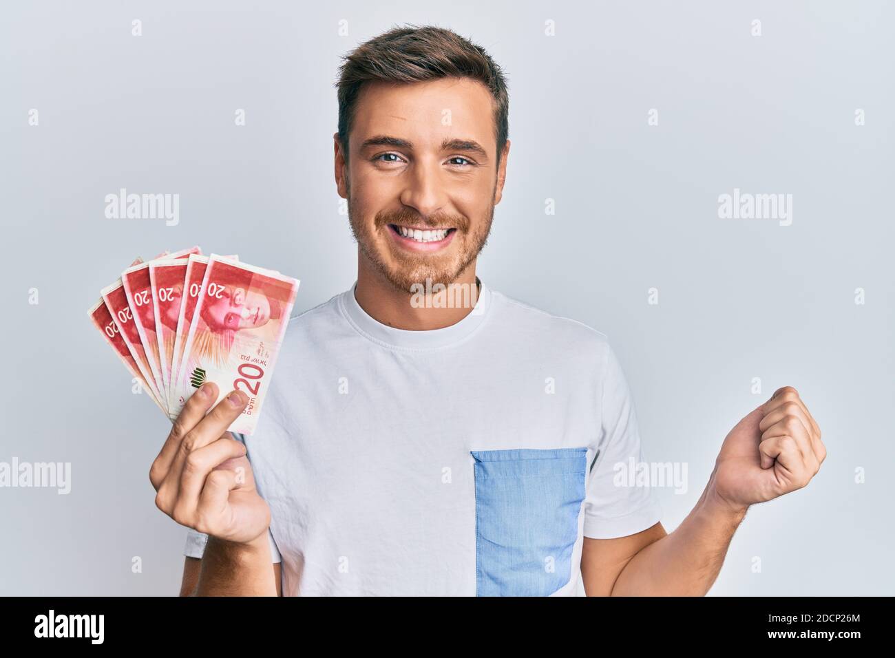 Handsome caucasian man holding israel shekels screaming proud ...