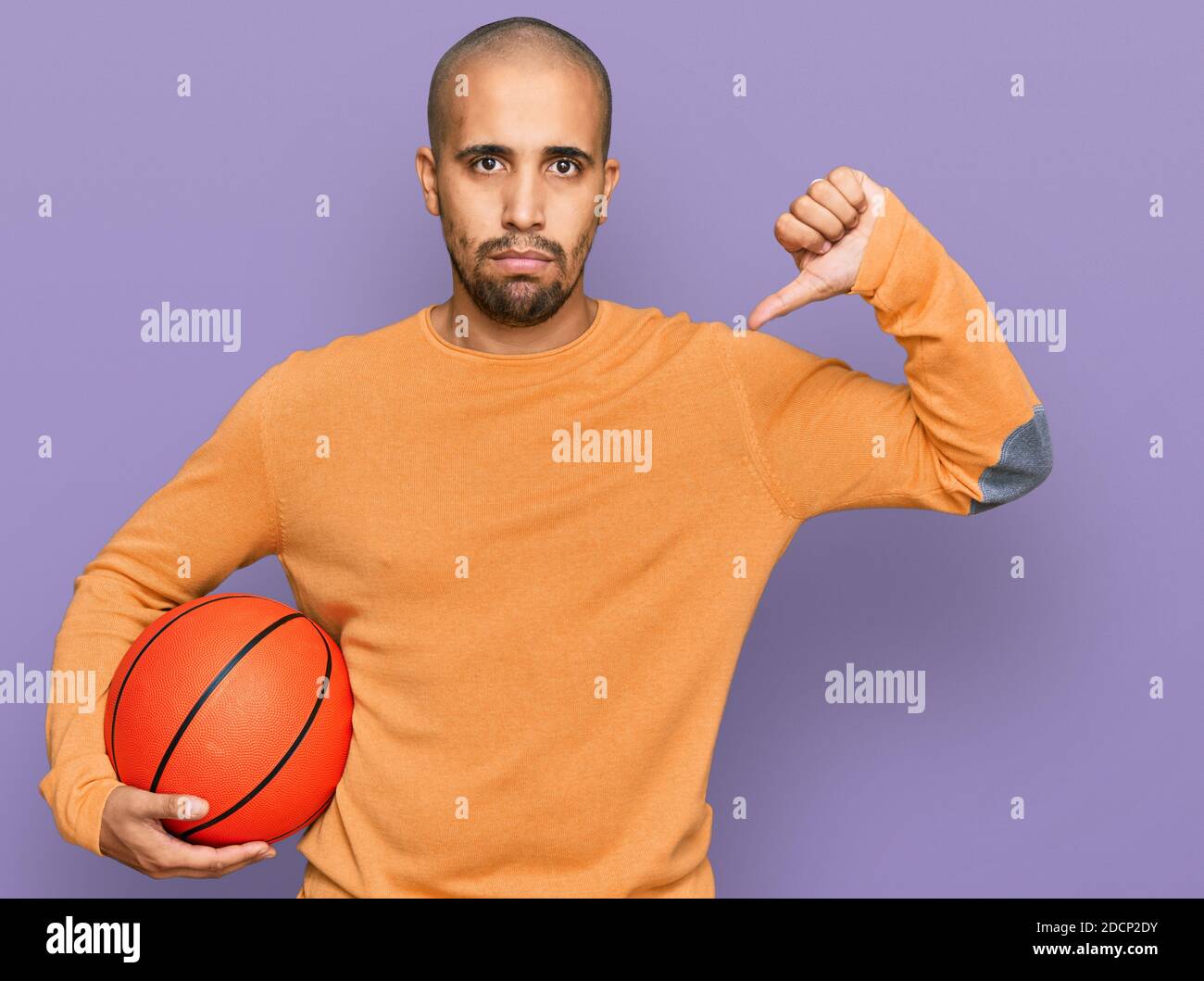 Hispanic adult man holding basketball ball with angry face, negative ...