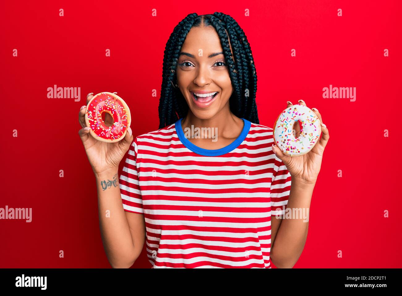 Beautiful hispanic woman holding tasty colorful doughnuts celebrating ...
