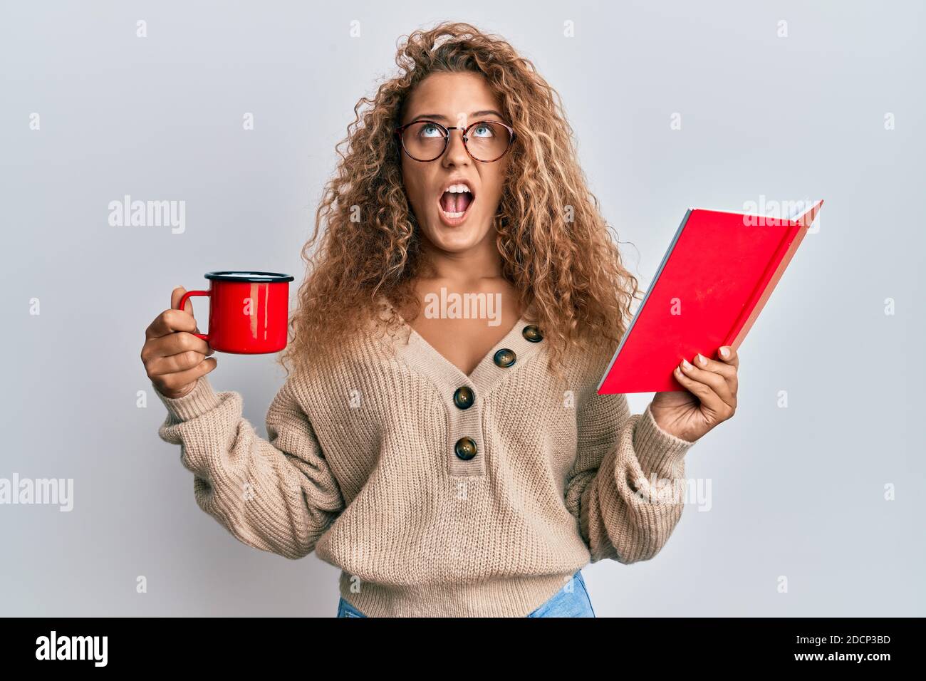 Beautiful caucasian teenager girl reading a book and drinking a cup of ...