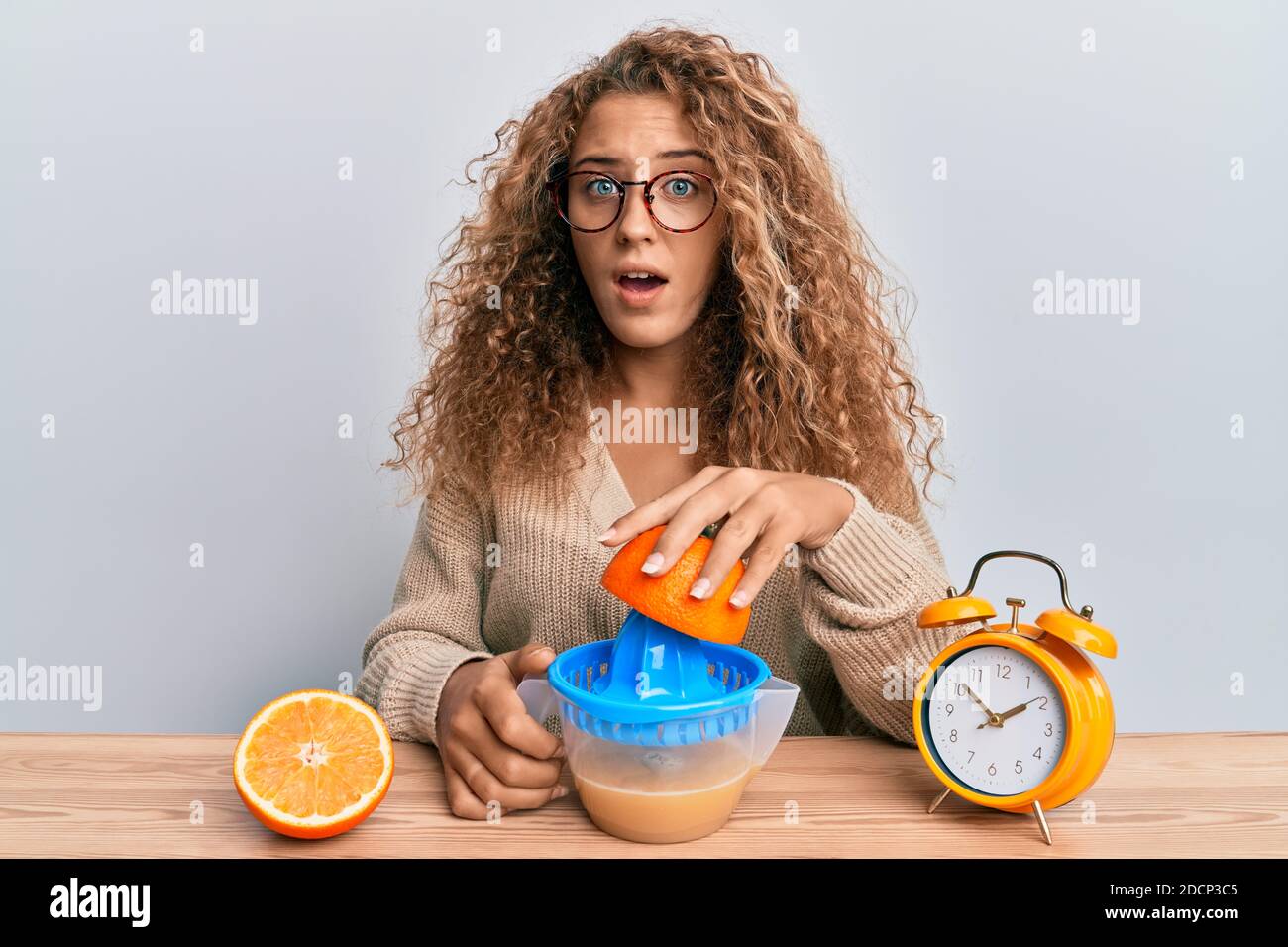 Beautiful caucasian teenager girl making orange juice for breakfast in ...