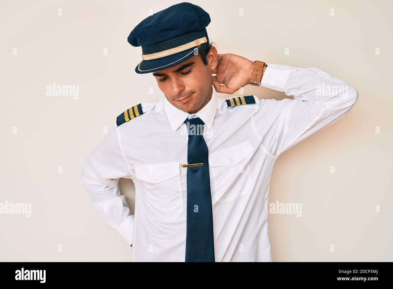 Young hispanic man wearing airplane pilot uniform suffering of neck ...
