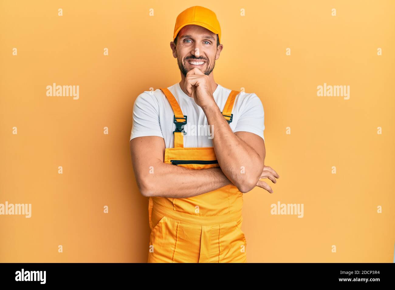 Young handsome man wearing handyman uniform over yellow background ...