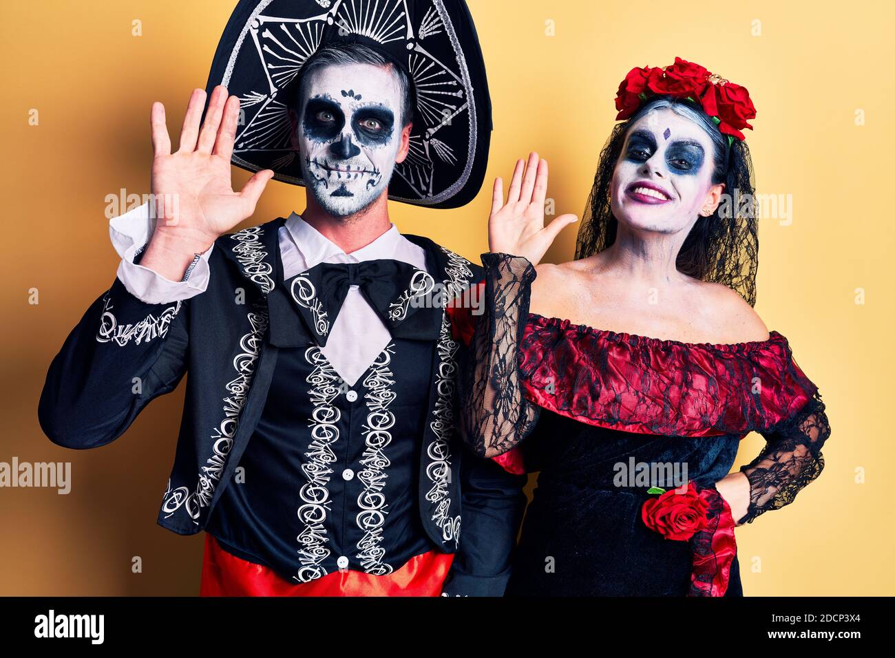 Young couple wearing mexican day of the dead costume over yellow ...