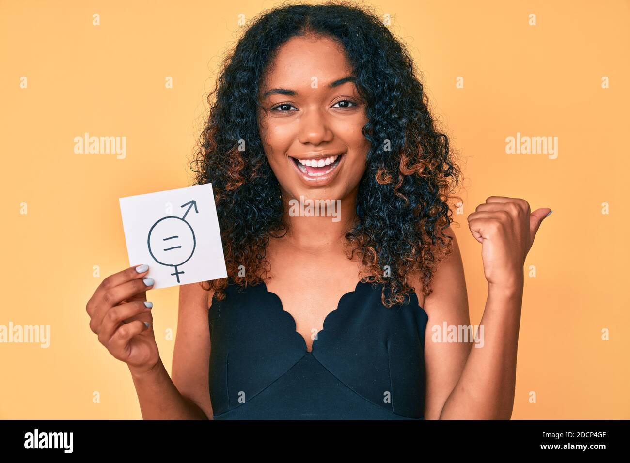 Young african american woman holding we are equal paper pointing thumb ...