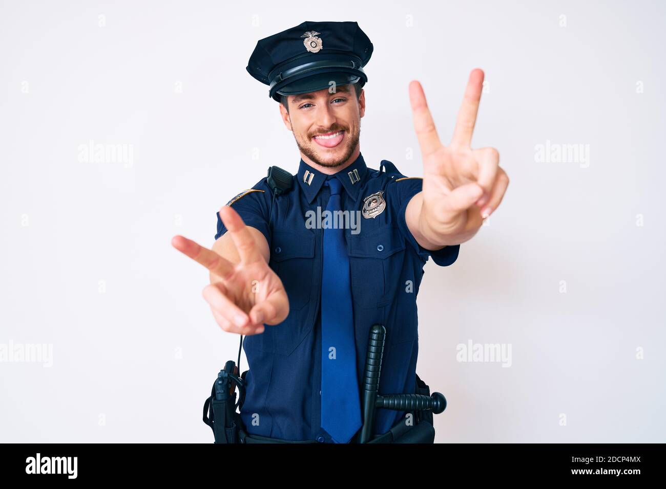 Young caucasian man wearing police uniform smiling with tongue out ...