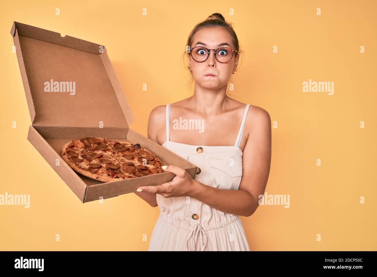 Beautiful caucasian woman holding tasty pepperoni pizza puffing cheeks ...