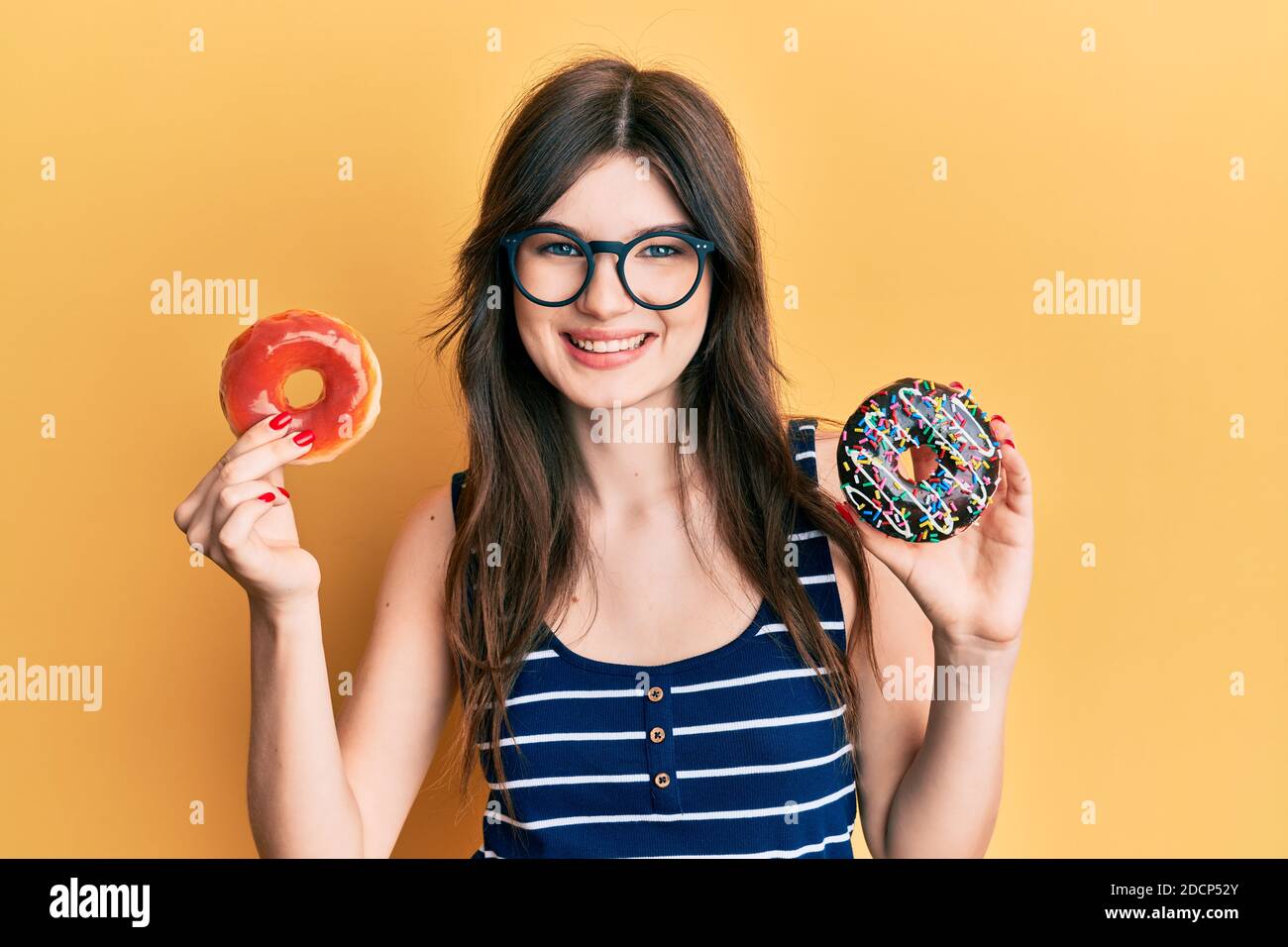 Young beautiful caucasian girl holding tasty colorful doughnuts smiling ...